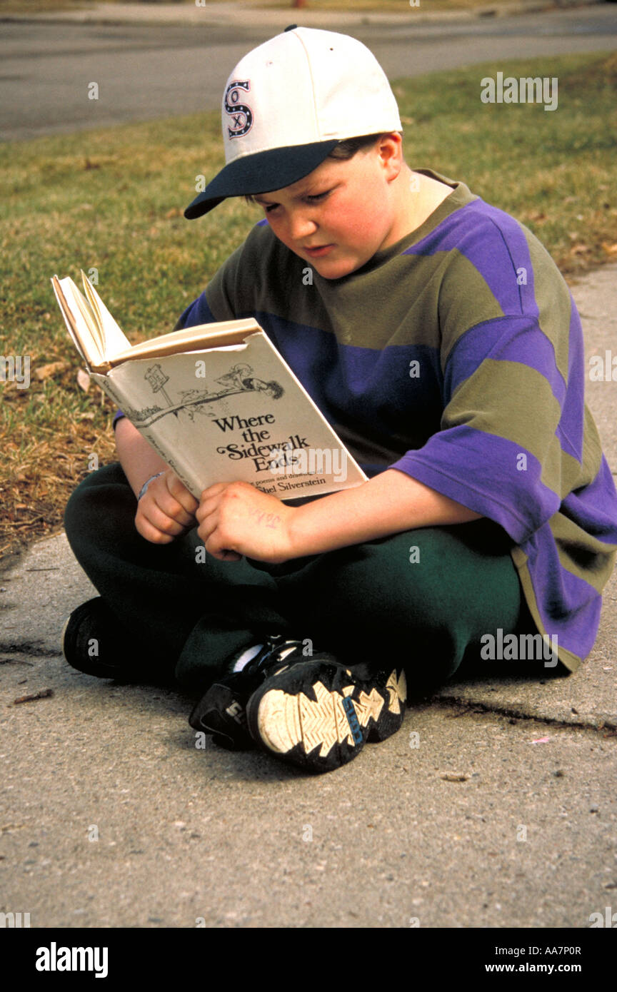 Grade school boy reading a book on the sidewalk. St. Paul, Minnesota ...