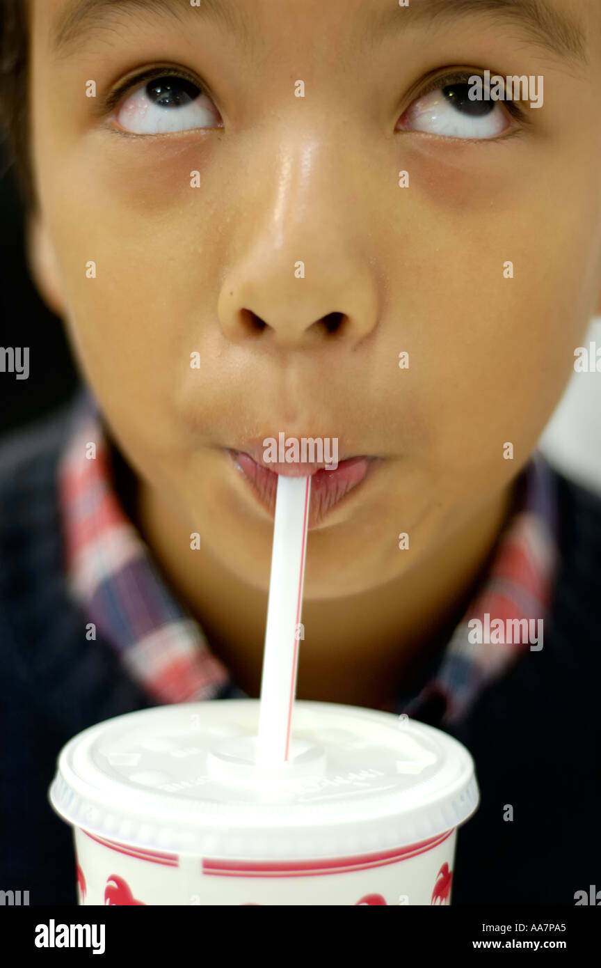 Boy drinking with straw looking up Stock Photo - Alamy