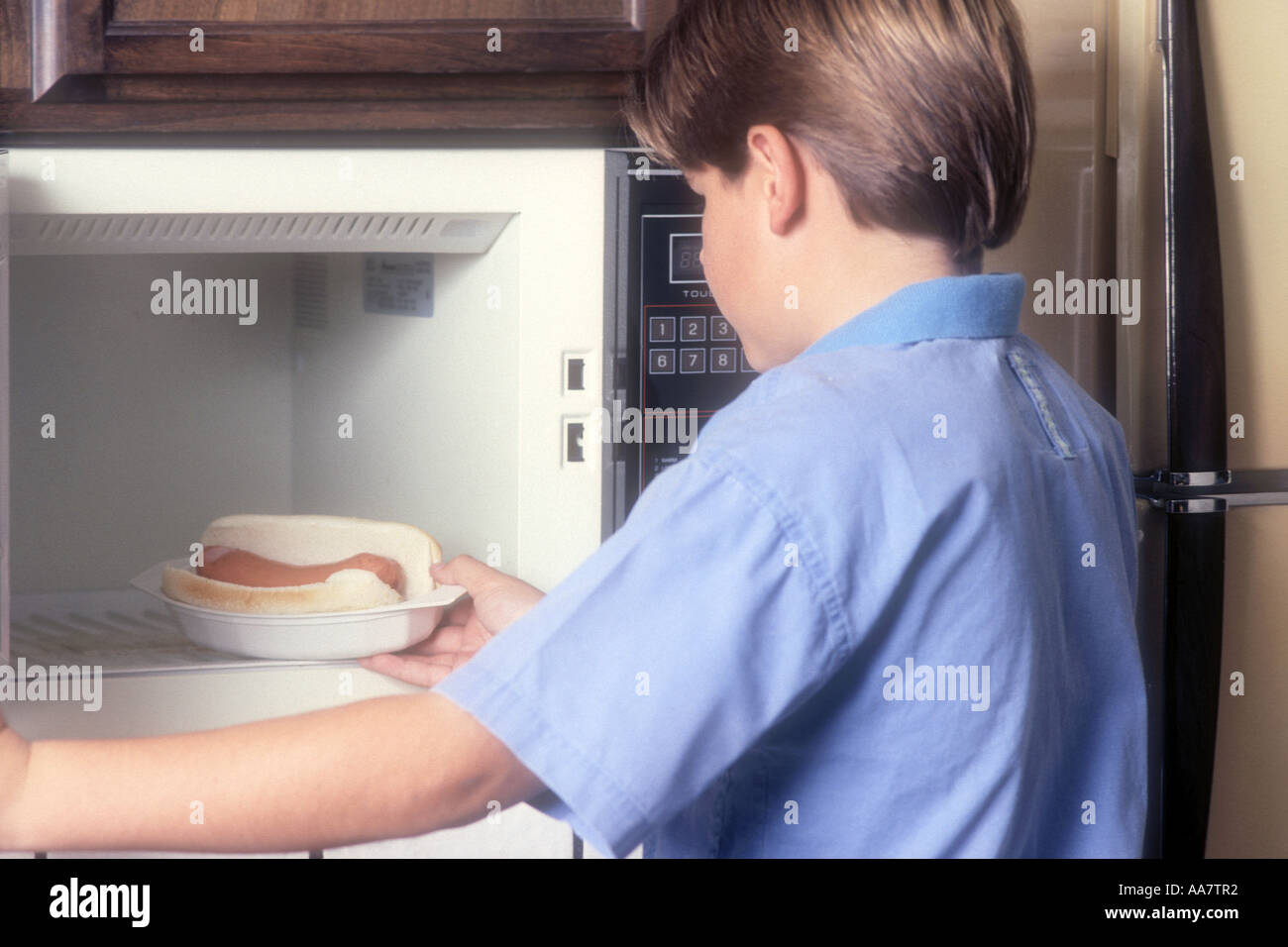 Teenage boy microwaving a hot dog Stock Photo - Alamy