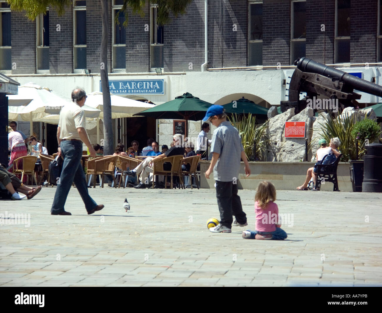 Little girl sitting on the ground and boys playing football, Casemates ...