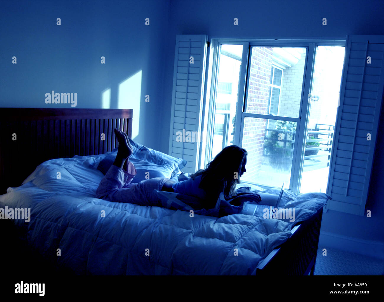 Horizontal color image of an adult female sitting in bedroom alone ...