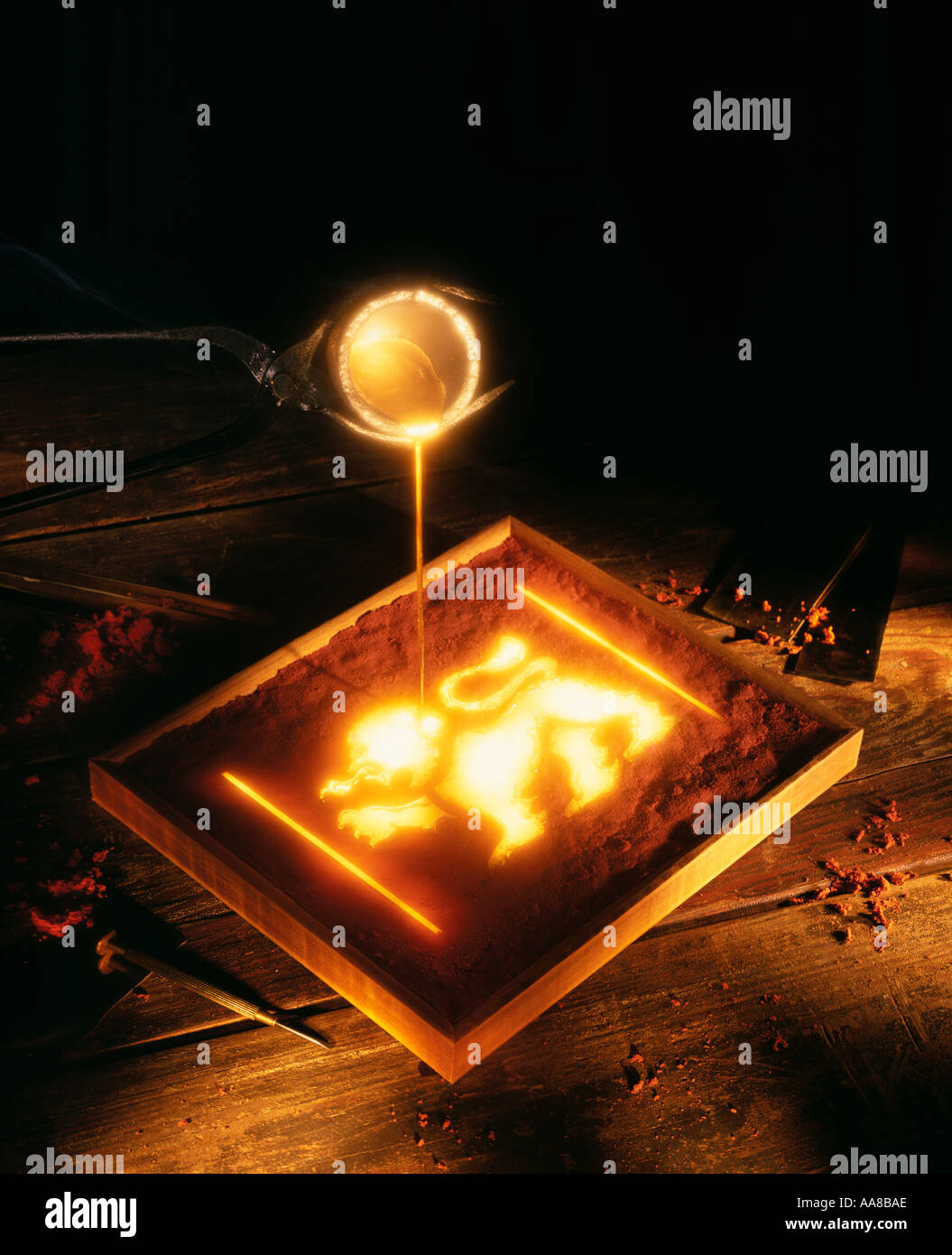 MOLTEN GOLD POURING FROM CRUCIBLE TO FORM CASTING IN SHAPE OF A LION ...