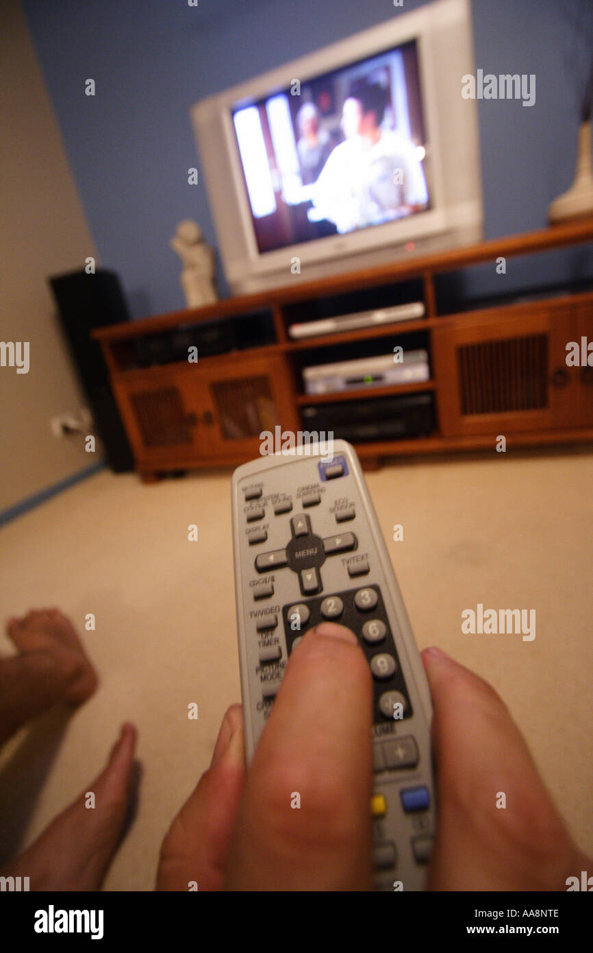 REMOTE CONTROL IN A MALE HAND POINTED AT A TELEVISION VERTICAL ...