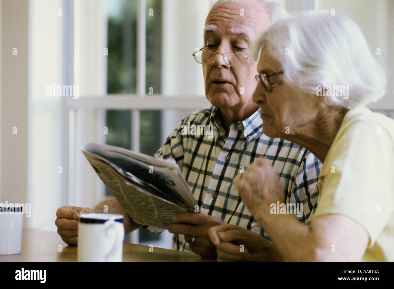 Senior couple reading a newspaper together Stock Photo - Alamy