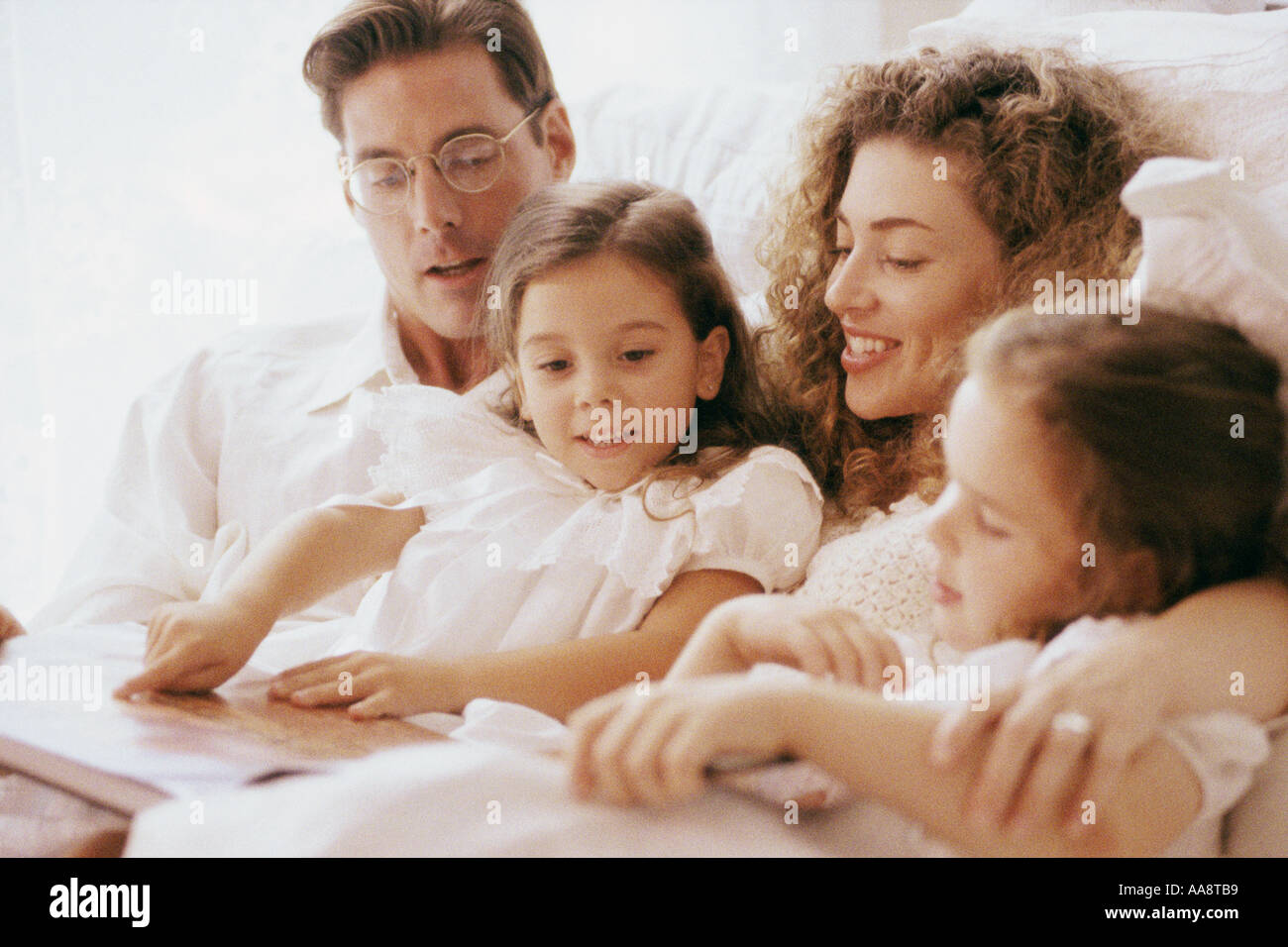 Parents and their two daughters together in bed Stock Photo - Alamy