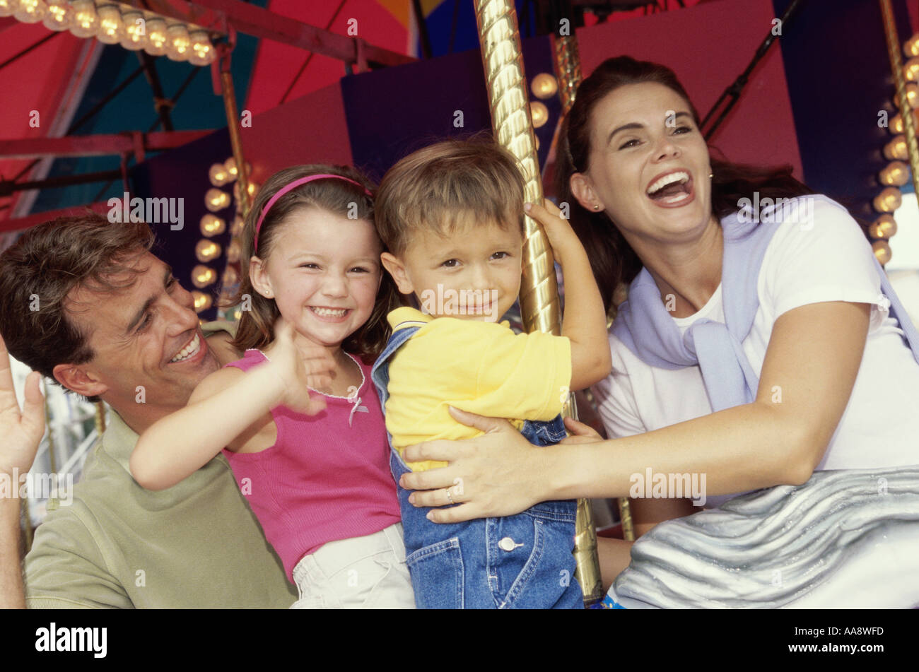 Young couple sitting on a carousel with their son and daughter Stock ...
