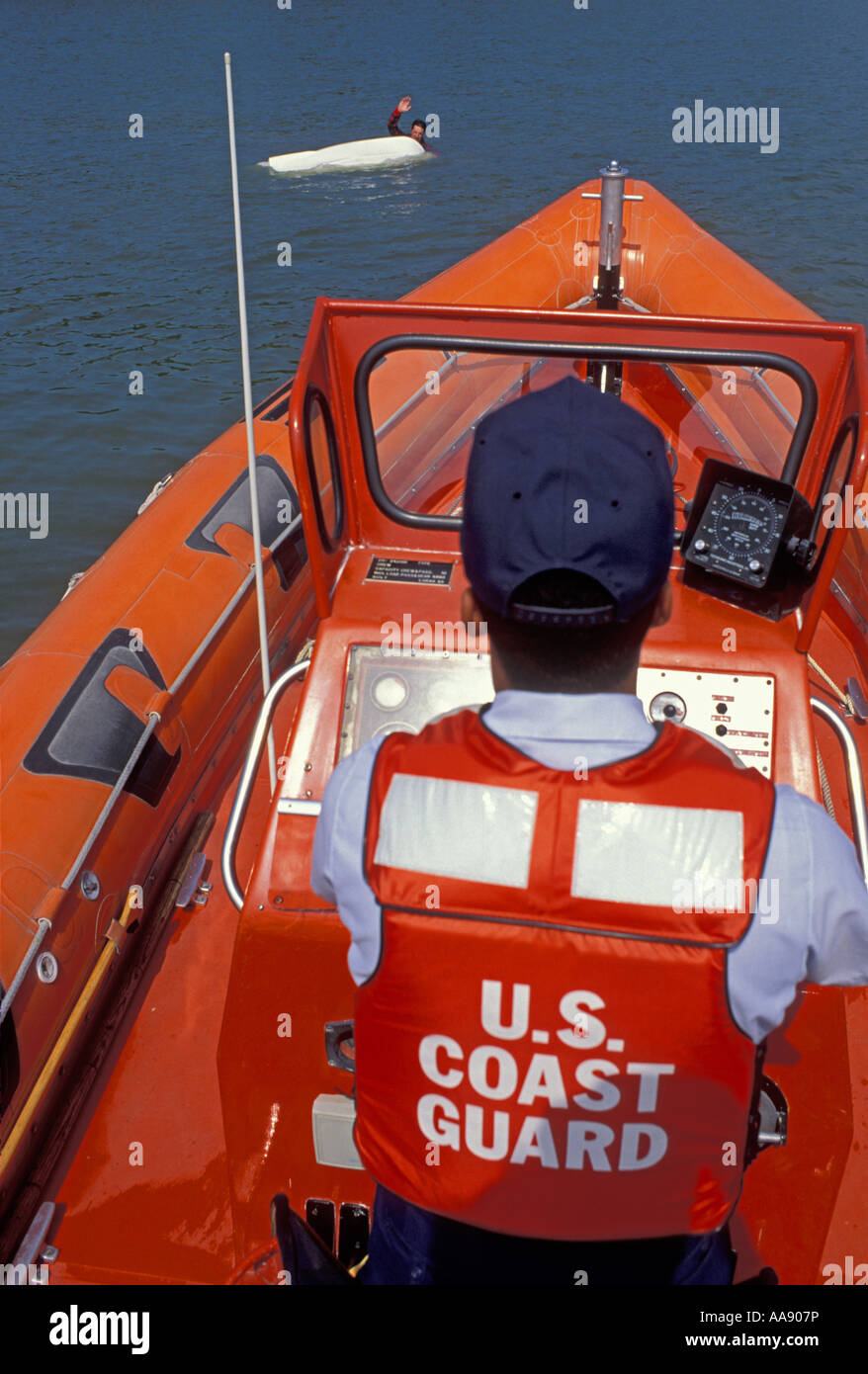 U S Coast Guard officer rescues a boater from an overturned water craft ...