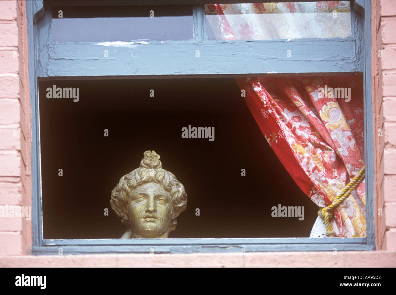 Classical statue looking out of window of house Stock Photo - Alamy