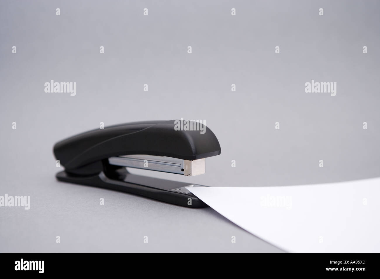 Black office stapler and sheet of white paper on grey background Stock ...