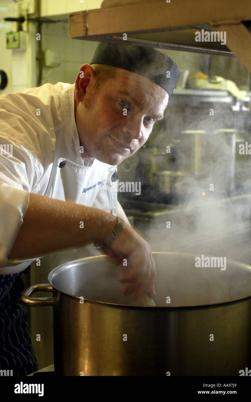 A CHEF COOKING A MEAL LEANS OVER A PAN WHICH IS STEAMING AND HE IS ...