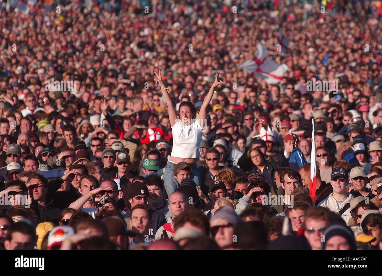 A GIRL CHEERS SAT ON HER BOYFRIENDS SHOULDERS IN A CROWD OF PEOPLE AT A ...