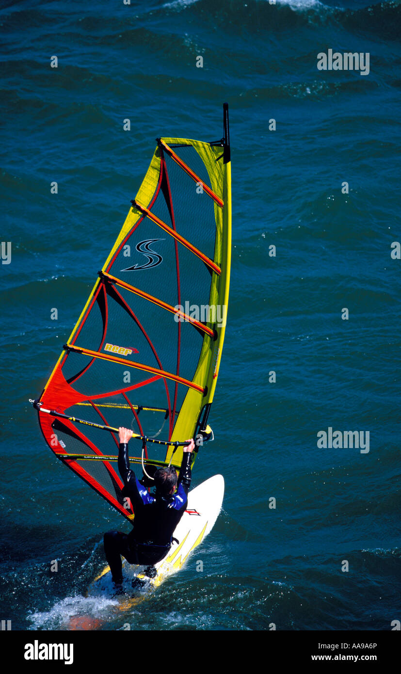 Generic shot of a male windsurfer pulling on his sail over deep water ...