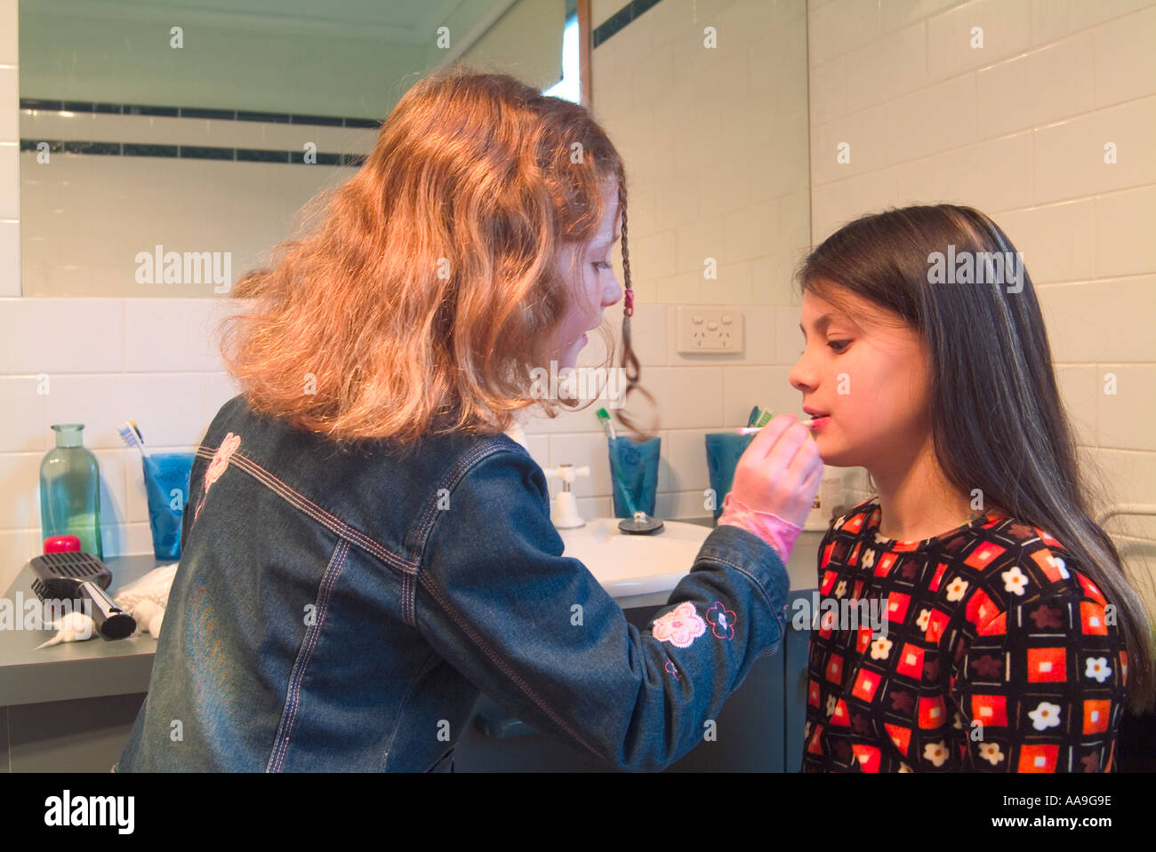 Two pretty 9 year old girls playing at putting on makeup Stock Photo ...