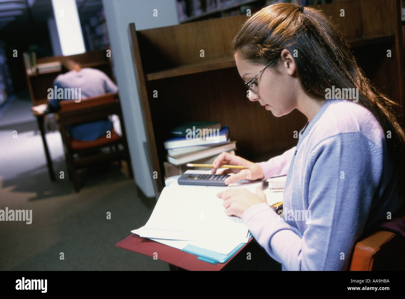 Teenage girl studying in a library Stock Photo - Alamy