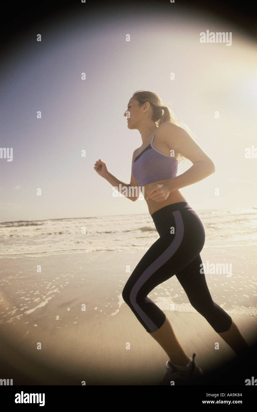 Side profile of a young woman jogging at the beach Stock Photo - Alamy