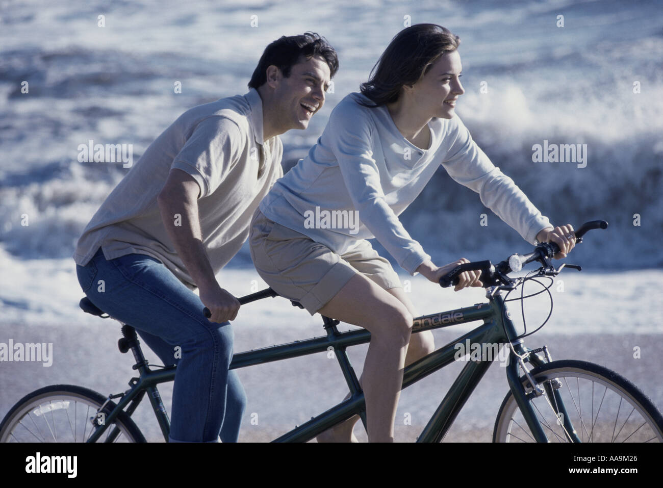 Young couple riding a tandem bicycle at the beach Stock Photo - Alamy