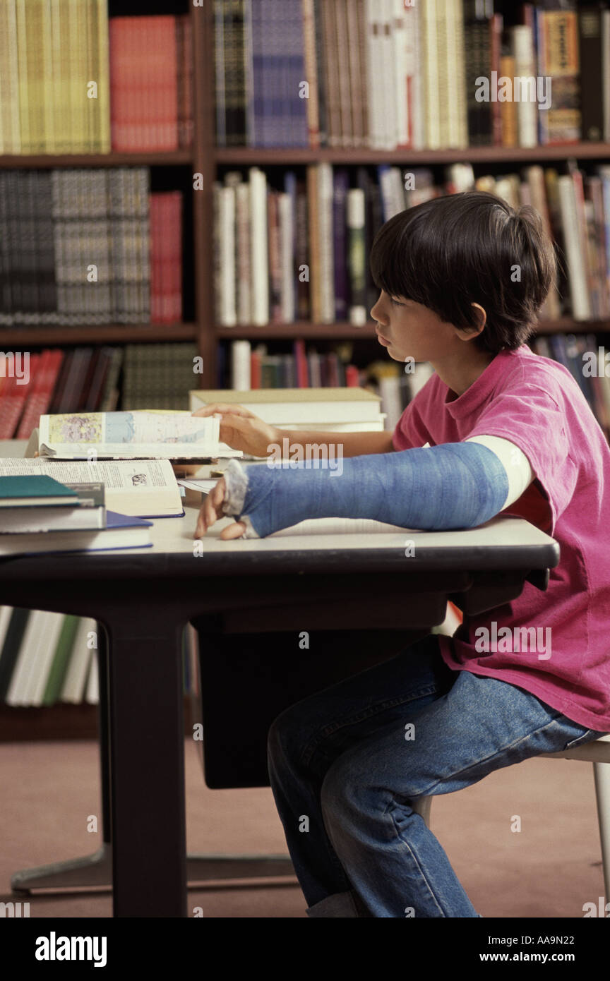 Boy sitting in a library and studying Stock Photo - Alamy