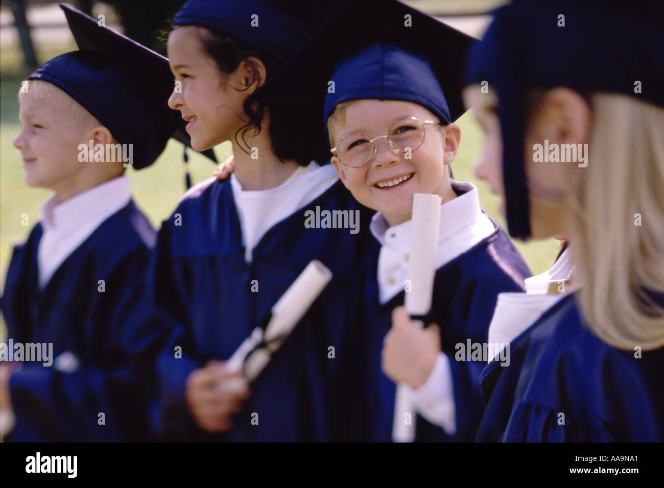 Children dressed in graduation outfits holding diplomas Stock Photo - Alamy