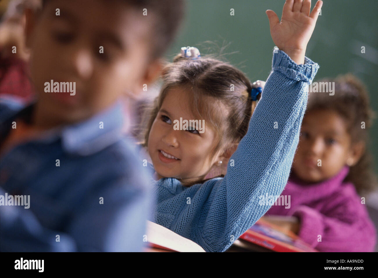 Girl raising her hand in class Stock Photo - Alamy
