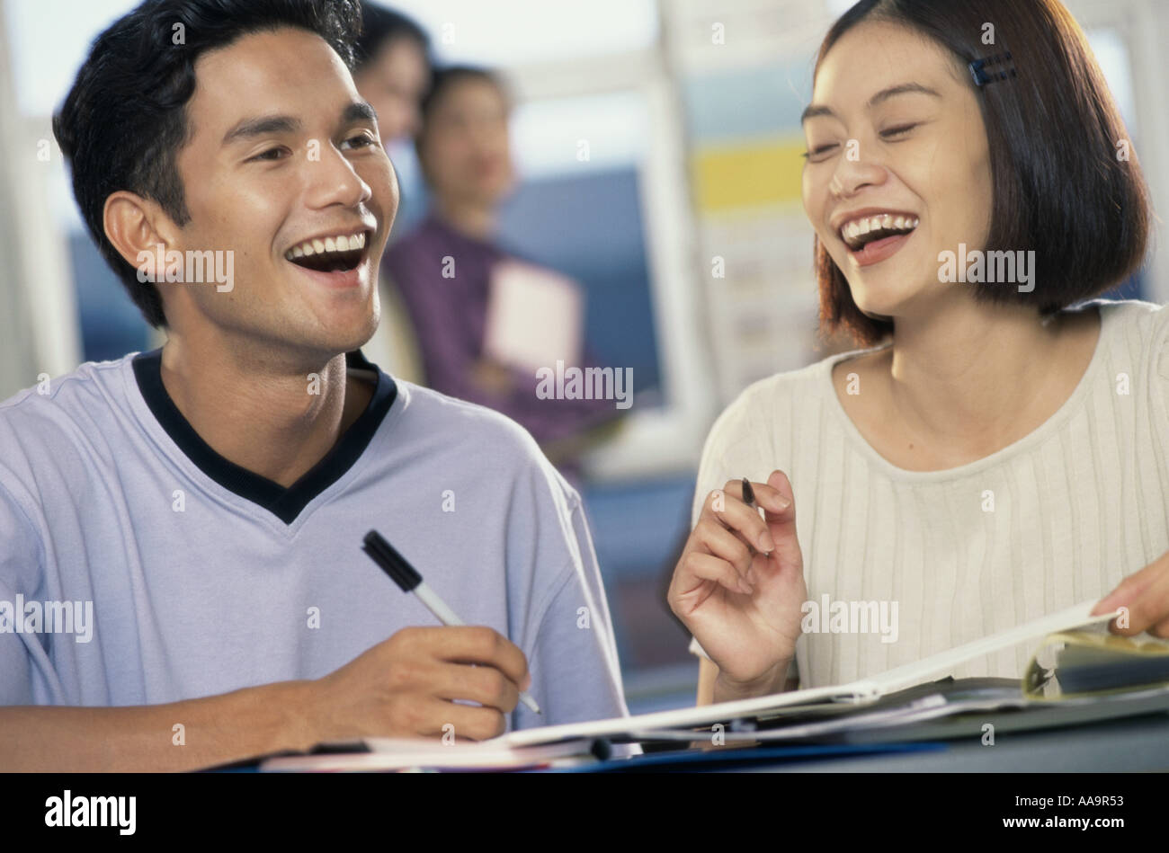Two teenage students laughing in a class Stock Photo - Alamy