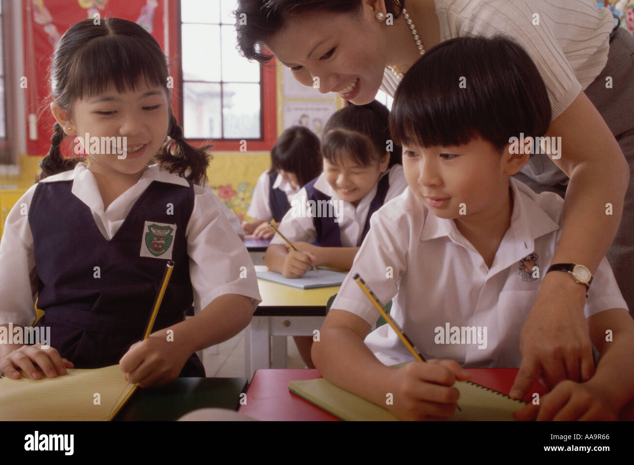 Teacher helping students in class Stock Photo - Alamy