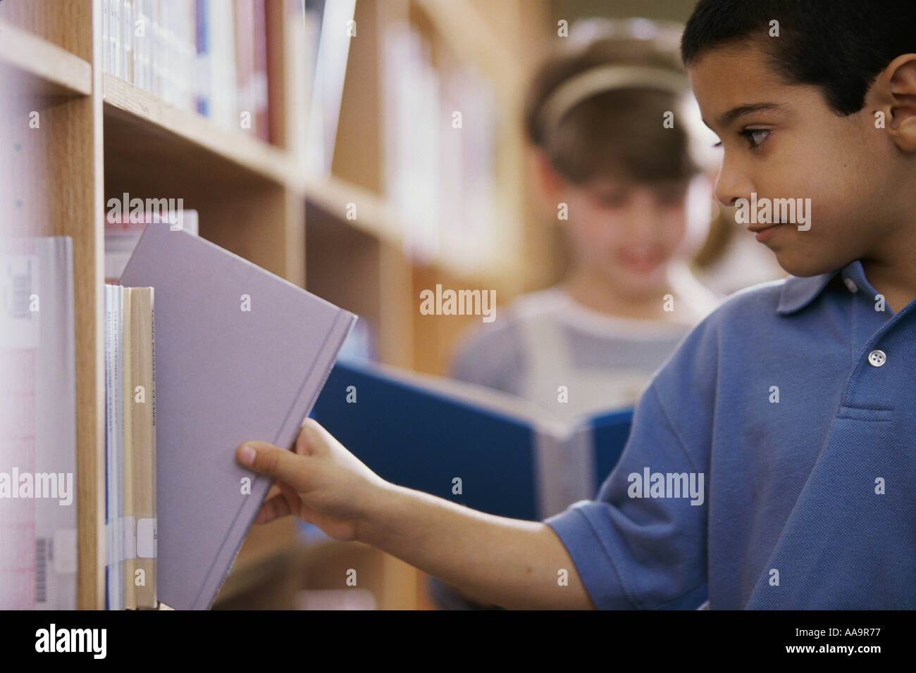 Boy taking a book from a shelf Stock Photo - Alamy