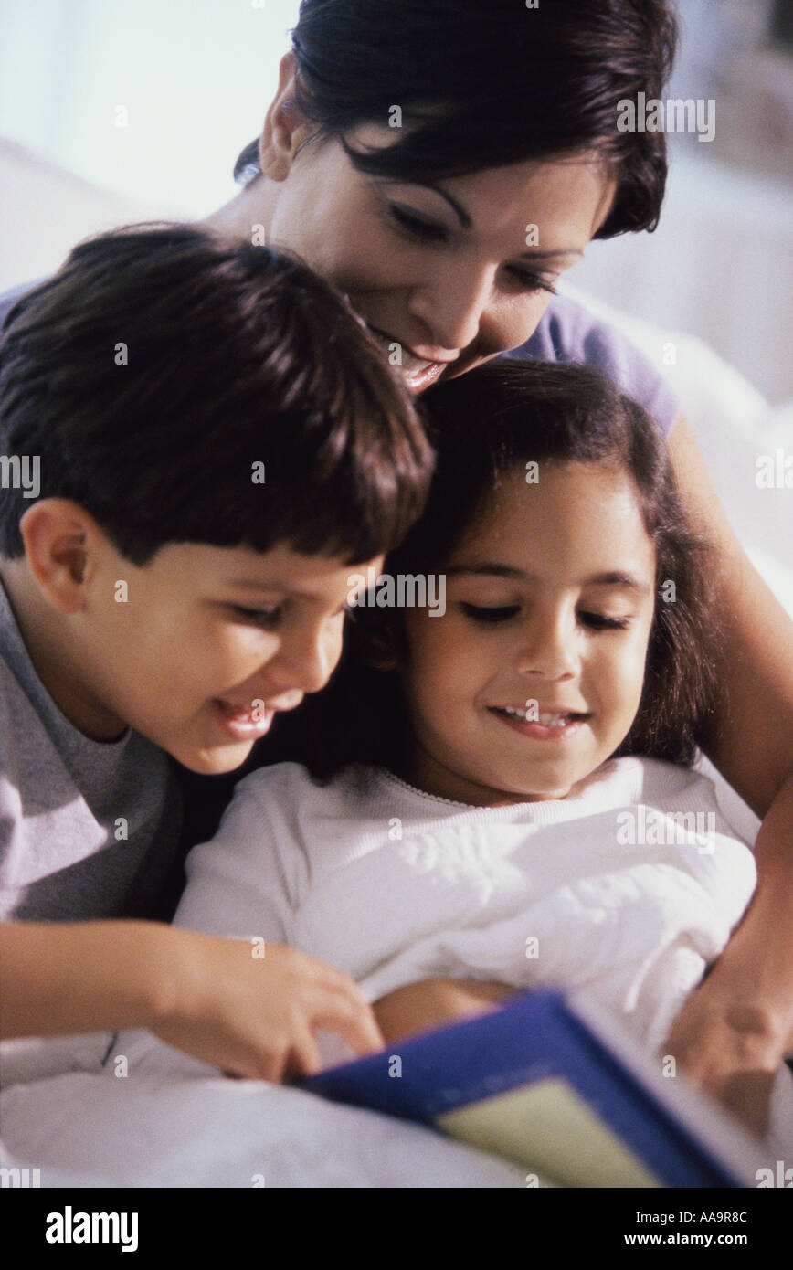Mother and her two children reading a book Stock Photo - Alamy