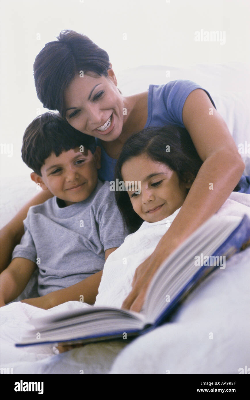 Mother and her two children reading a book Stock Photo - Alamy