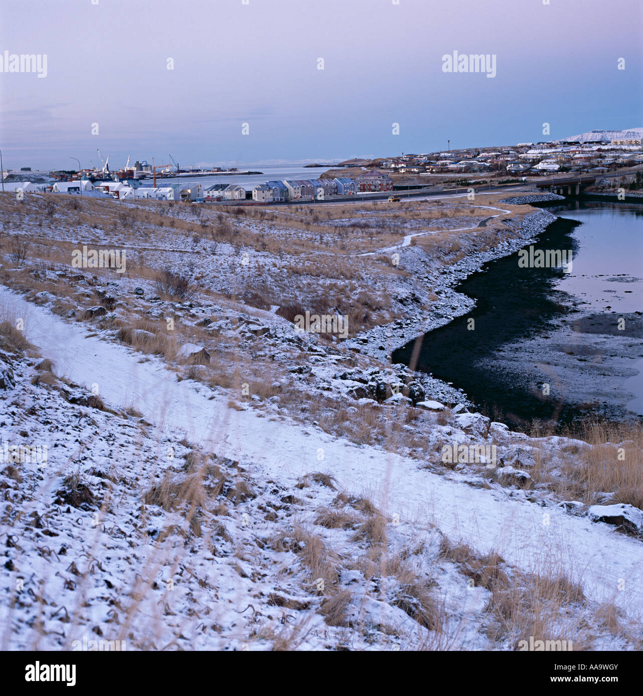 View of snow covered paths and houses plus black volcanic rock in ...