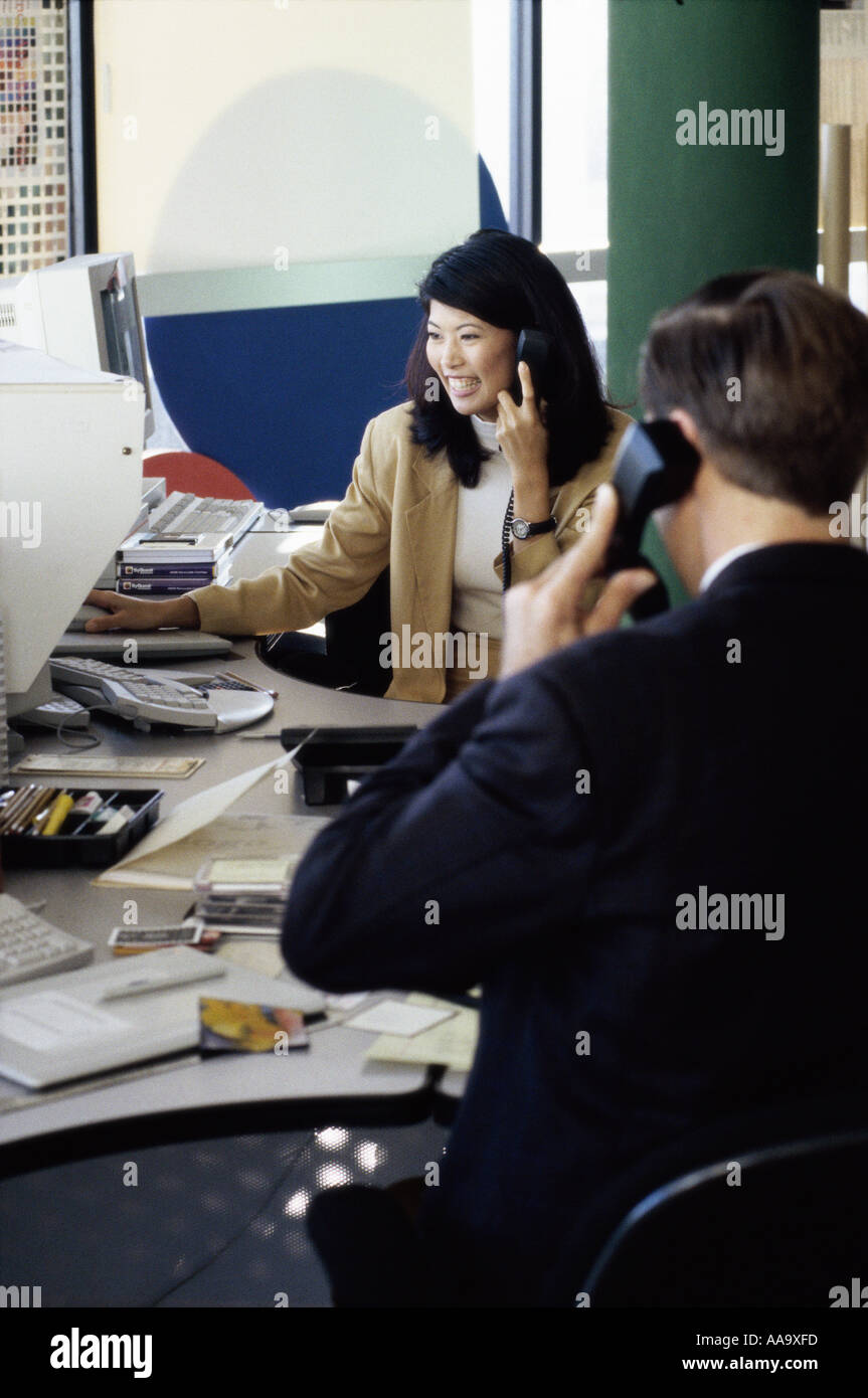 Two business executives talking on the landline telephone in the office ...