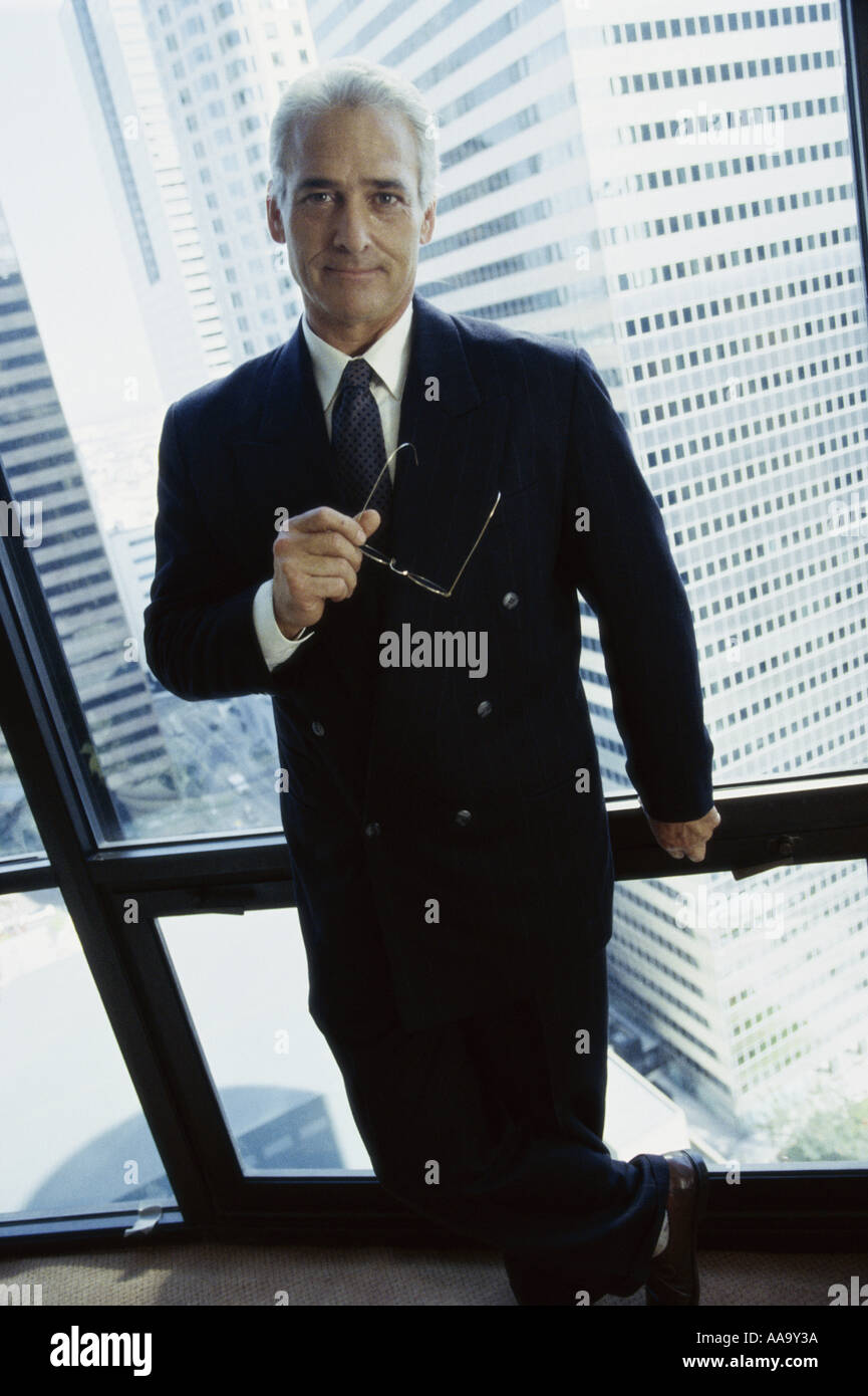 Portrait smiling businessman leaning against window hi-res stock ...