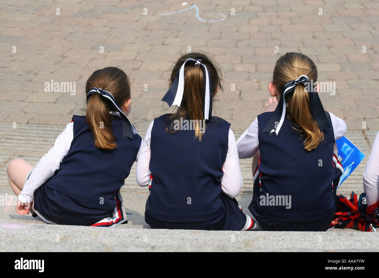 The backs of three young girls sat watching a parade Stock Photo - Alamy