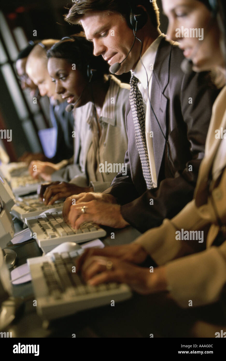 Row of customer service representatives sitting in front of computer ...