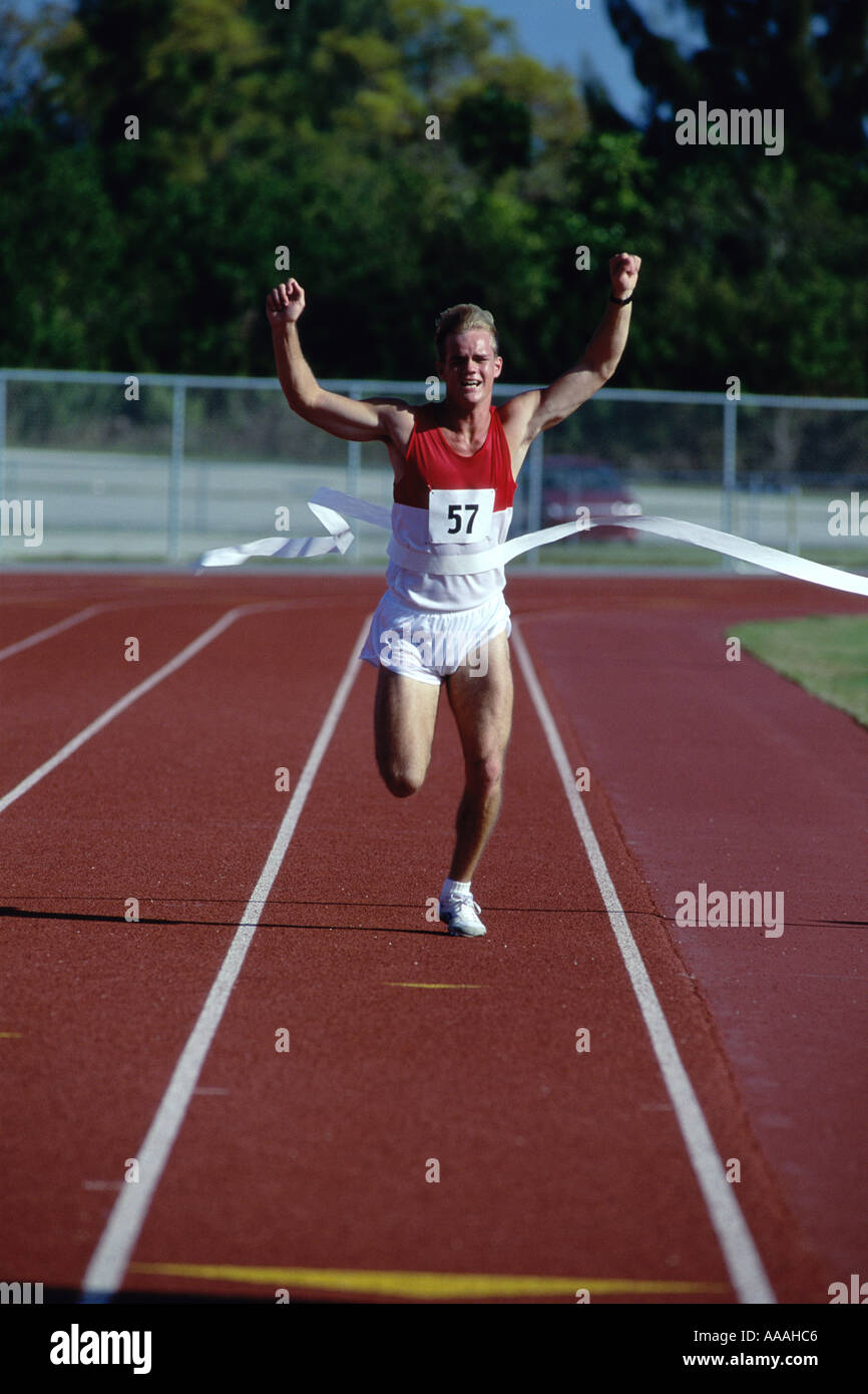 Portrait of a male runner crossing the finishing line with his arms ...