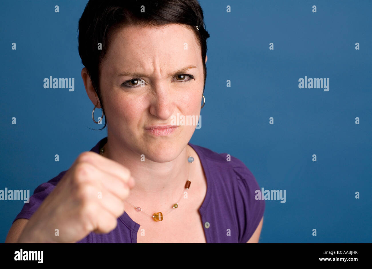 Aggressive young woman making a fist and looking tough Stock Photo - Alamy