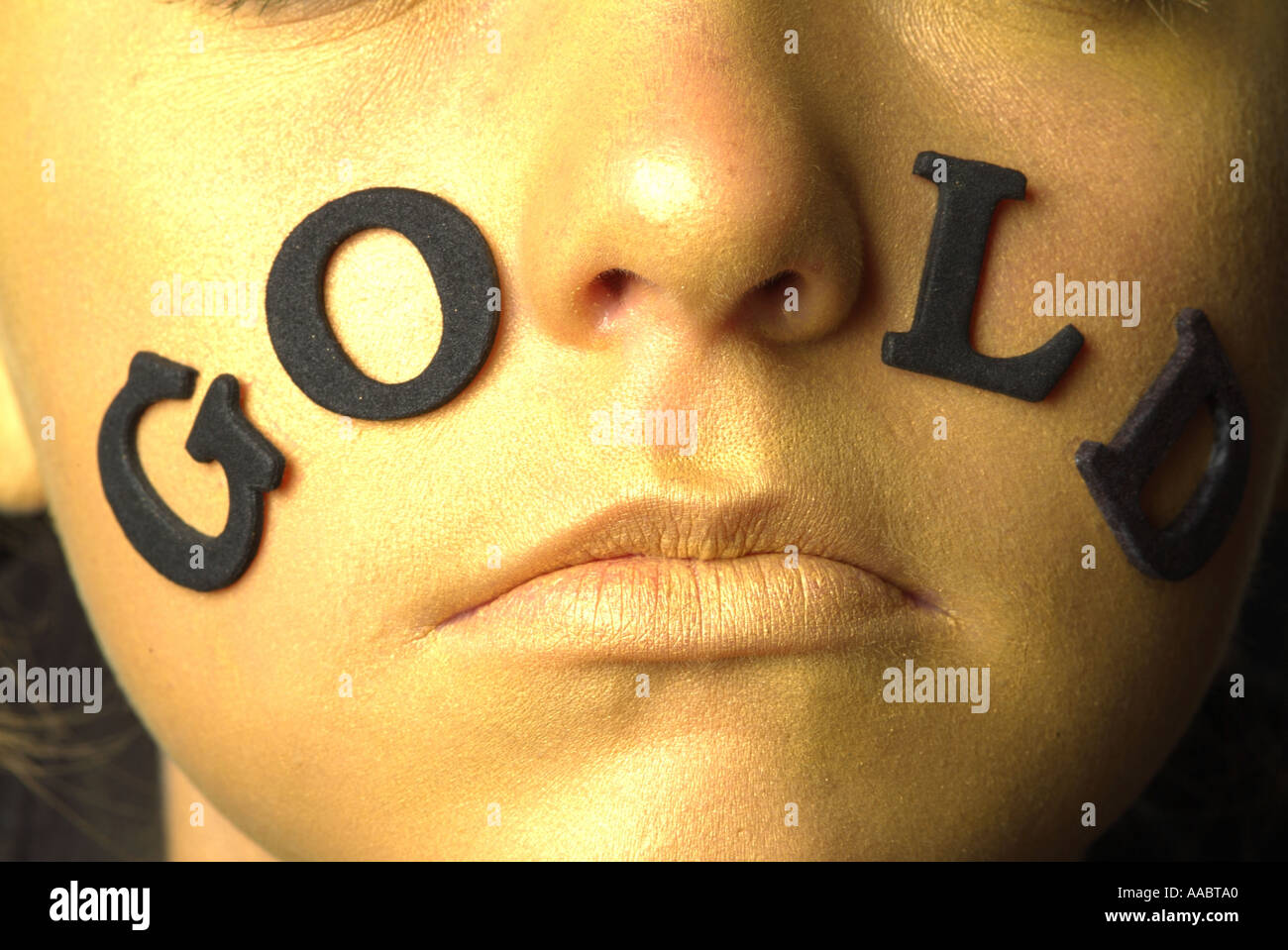 gold face girl closeup of nose mouth with the lettering GOLD Stock ...
