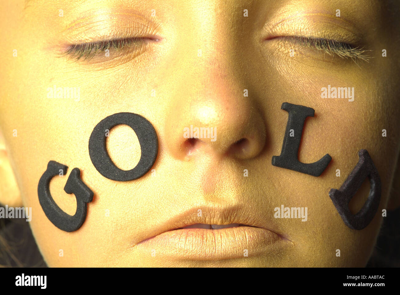 gold face girl closeup of eyes nose mouth with the lettering GOLD Stock ...