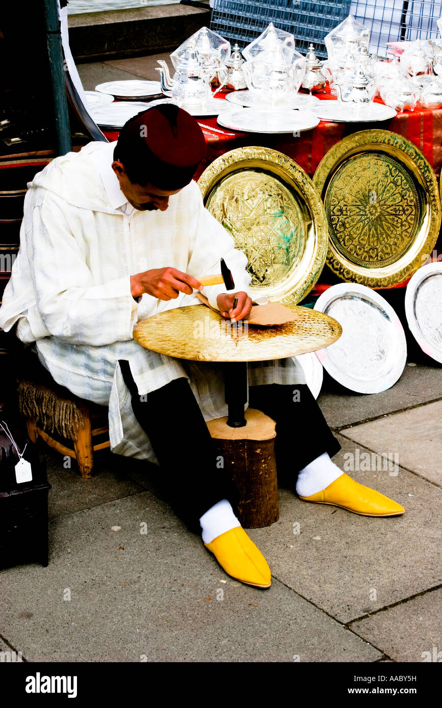 A Morrocan metal worker on the South Bank of the Thames hammers a ...
