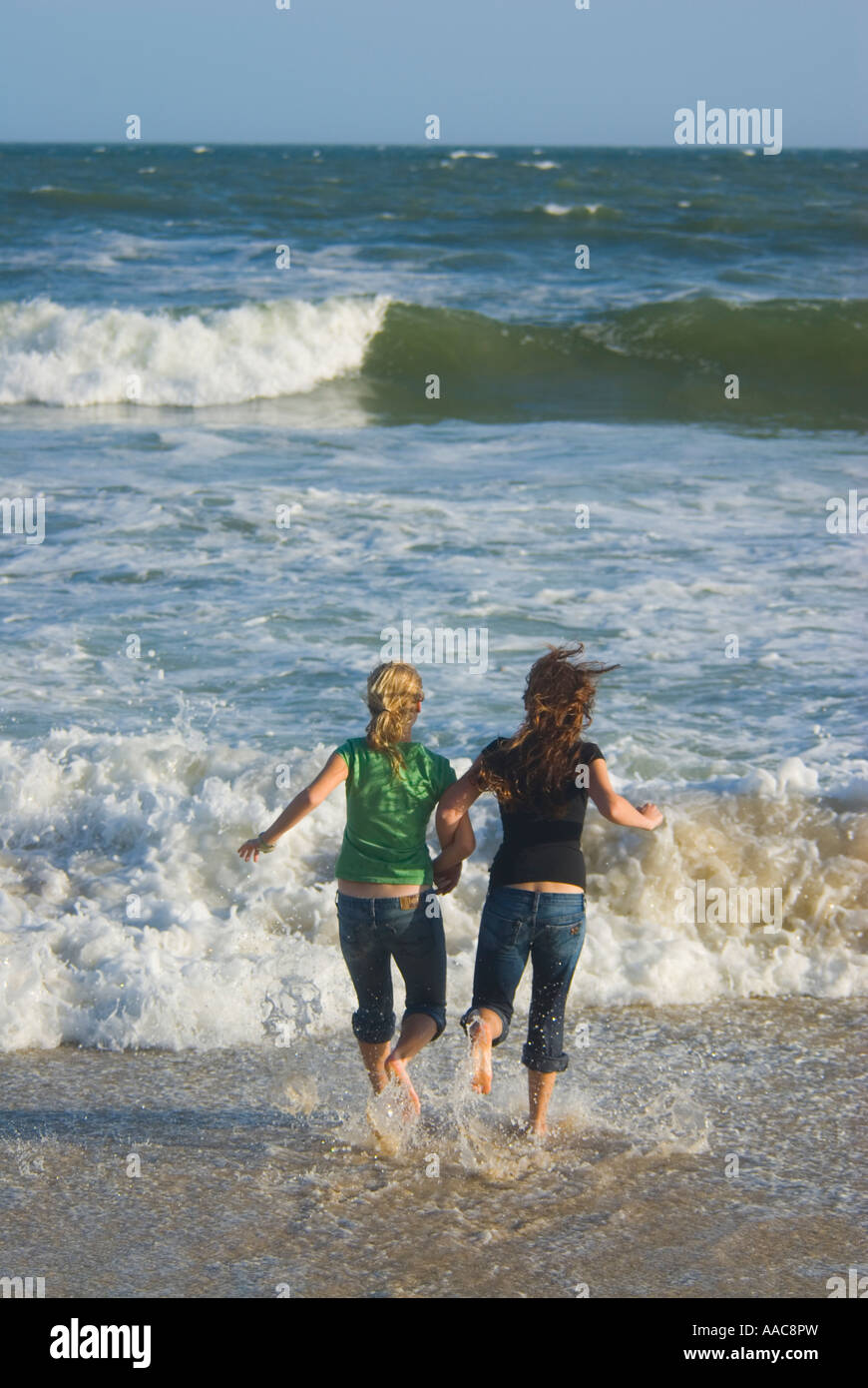 two clothed teenage girls running into sea Stock Photo - Alamy