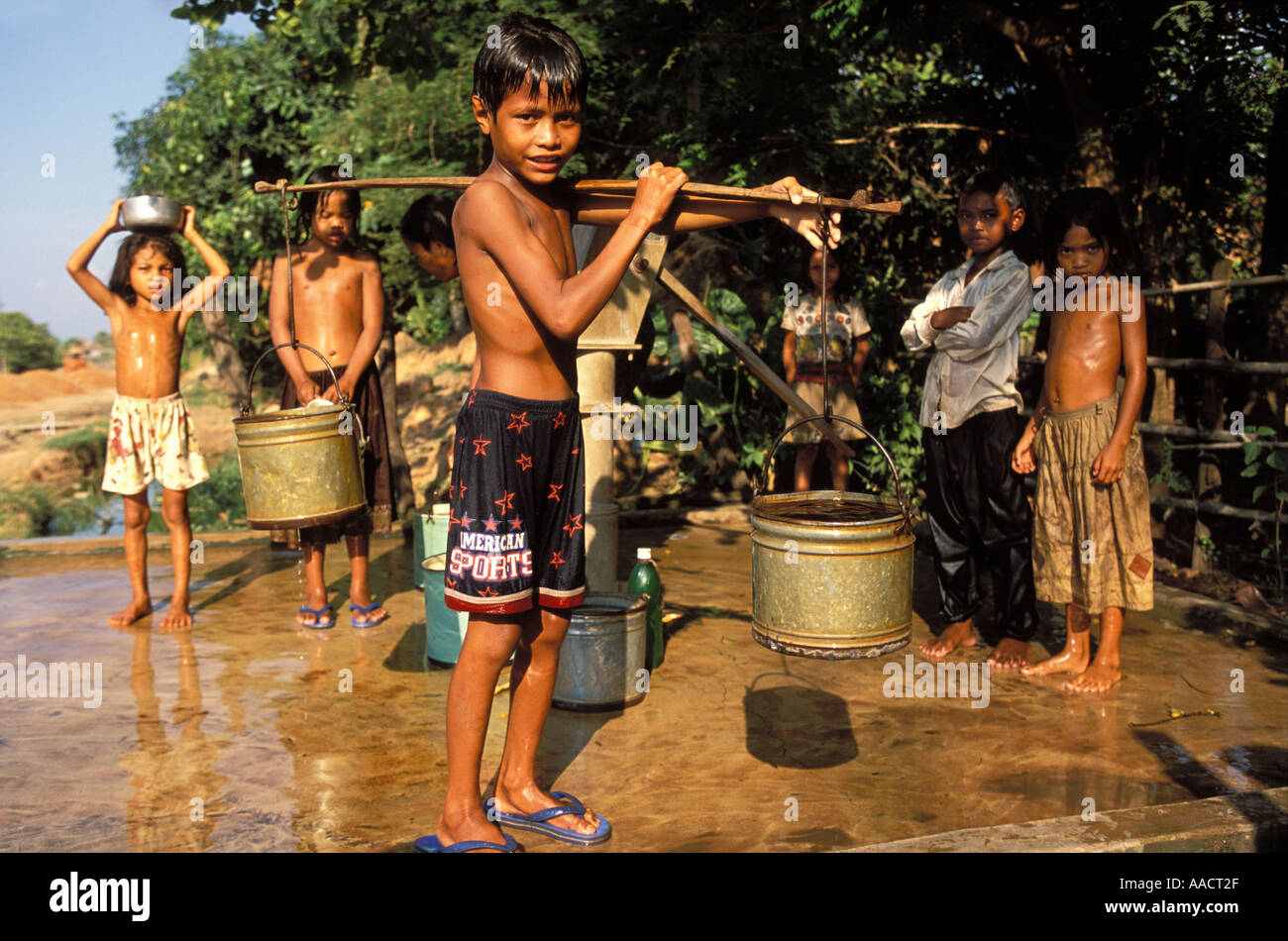 Cambodian children hoist water from a well in remote rural countryside ...
