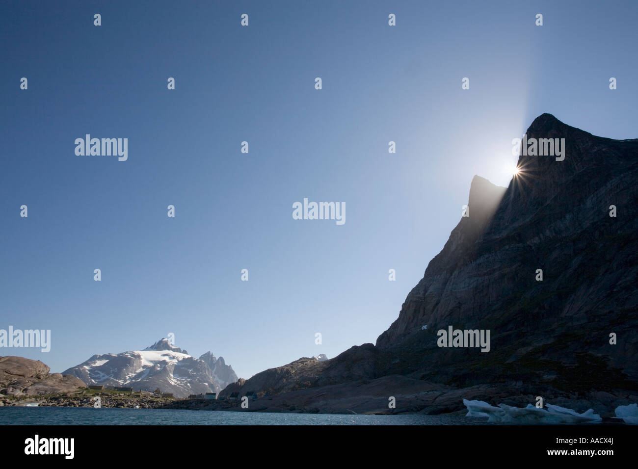 Greenland Aappilattoq Setting sun shines through steep mountains lining ...
