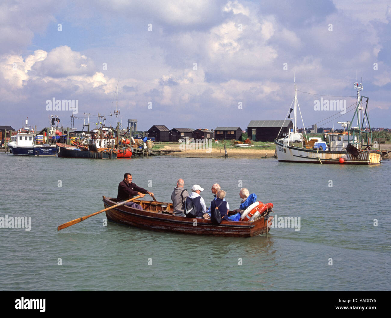 Walberswick close up ferry man in boat rowing group of people across ...