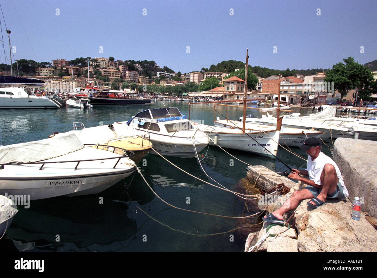 An angler fishes in the harbour at the seaside town of Port de Soller ...