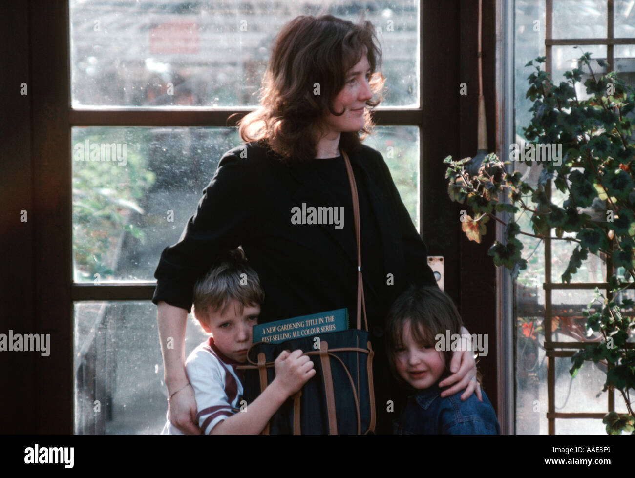 Two small children cling to their mother who has an arm around each of ...