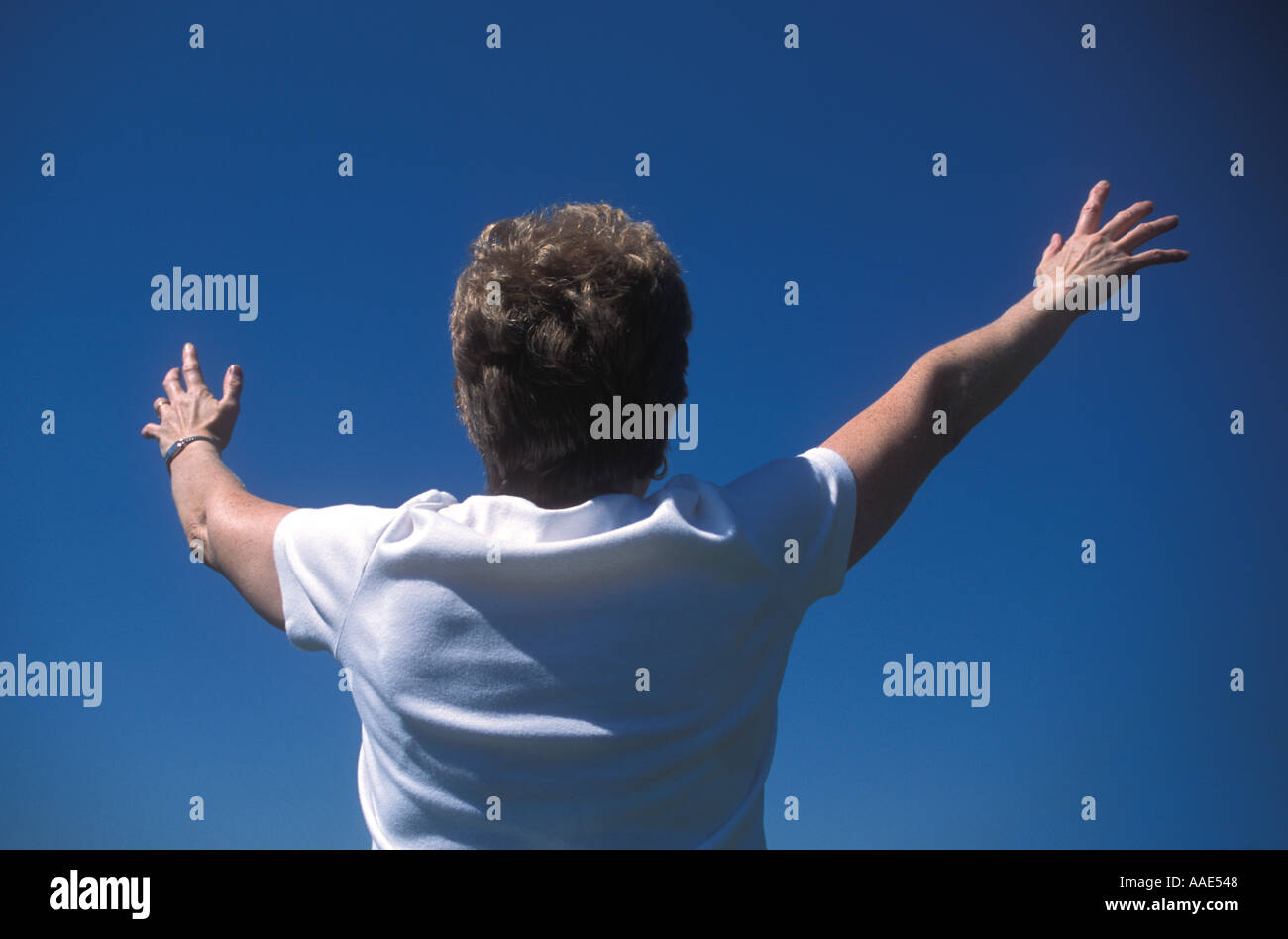 Woman arms raised waving and looking up at blue sky Stock Photo - Alamy