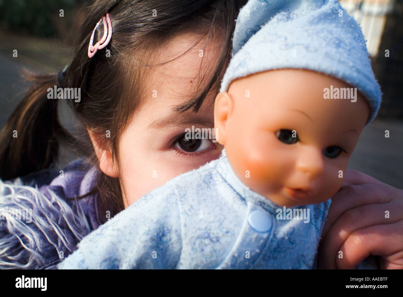 Young child hiding behind her doll Stock Photo - Alamy