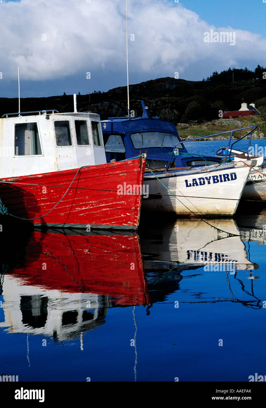 small fishing boats tied together at a small sea inlet on irish south ...