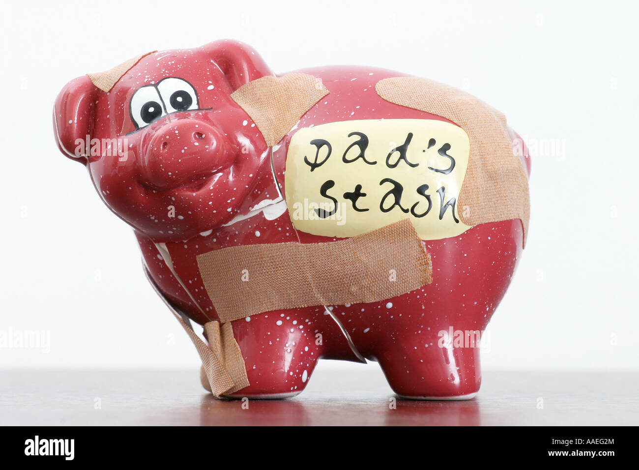 A broken piggy bank held together with adhesive plasters with a white ...