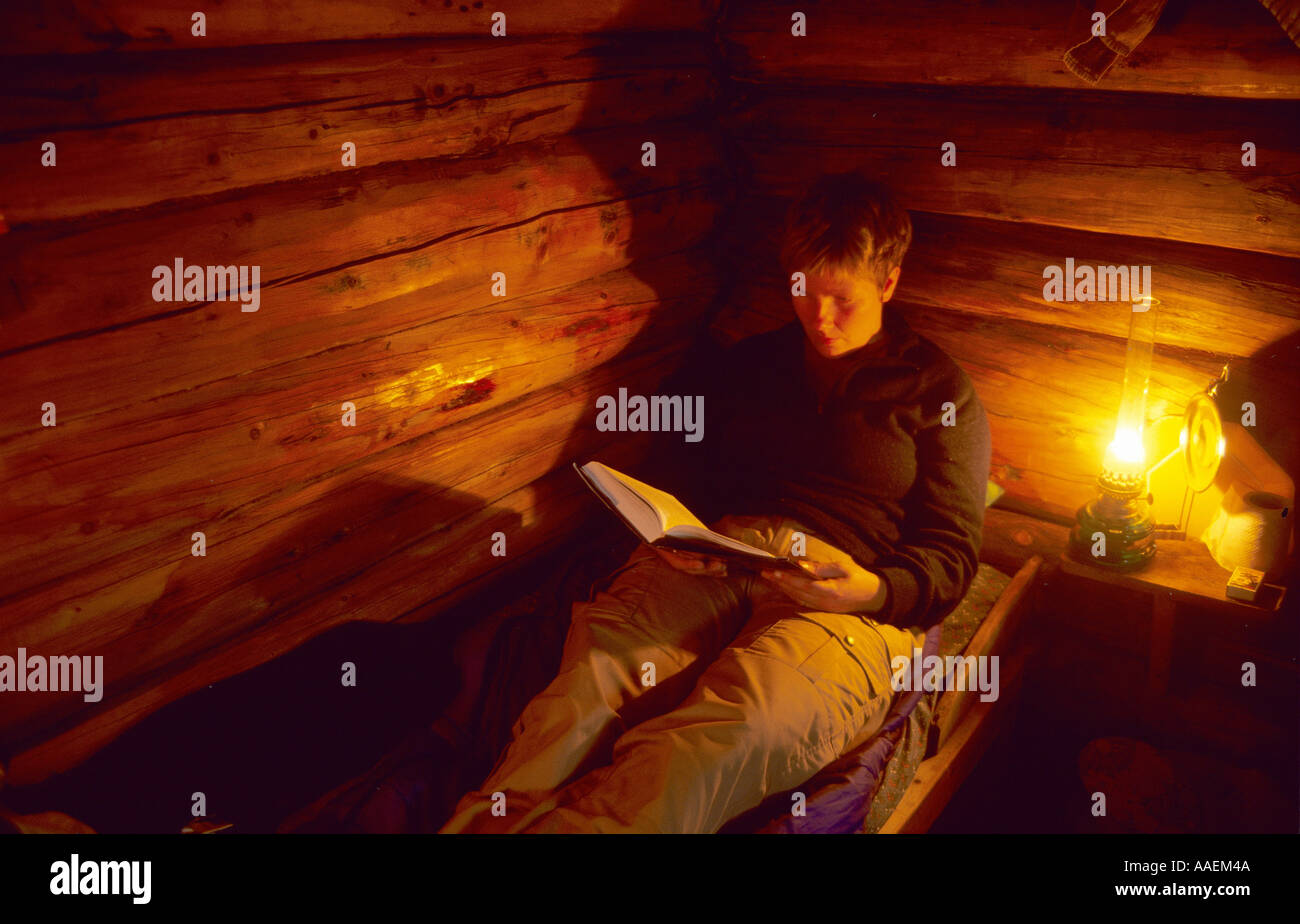 Woman reading book in the light of a kerosene lamp Stock Photo - Alamy