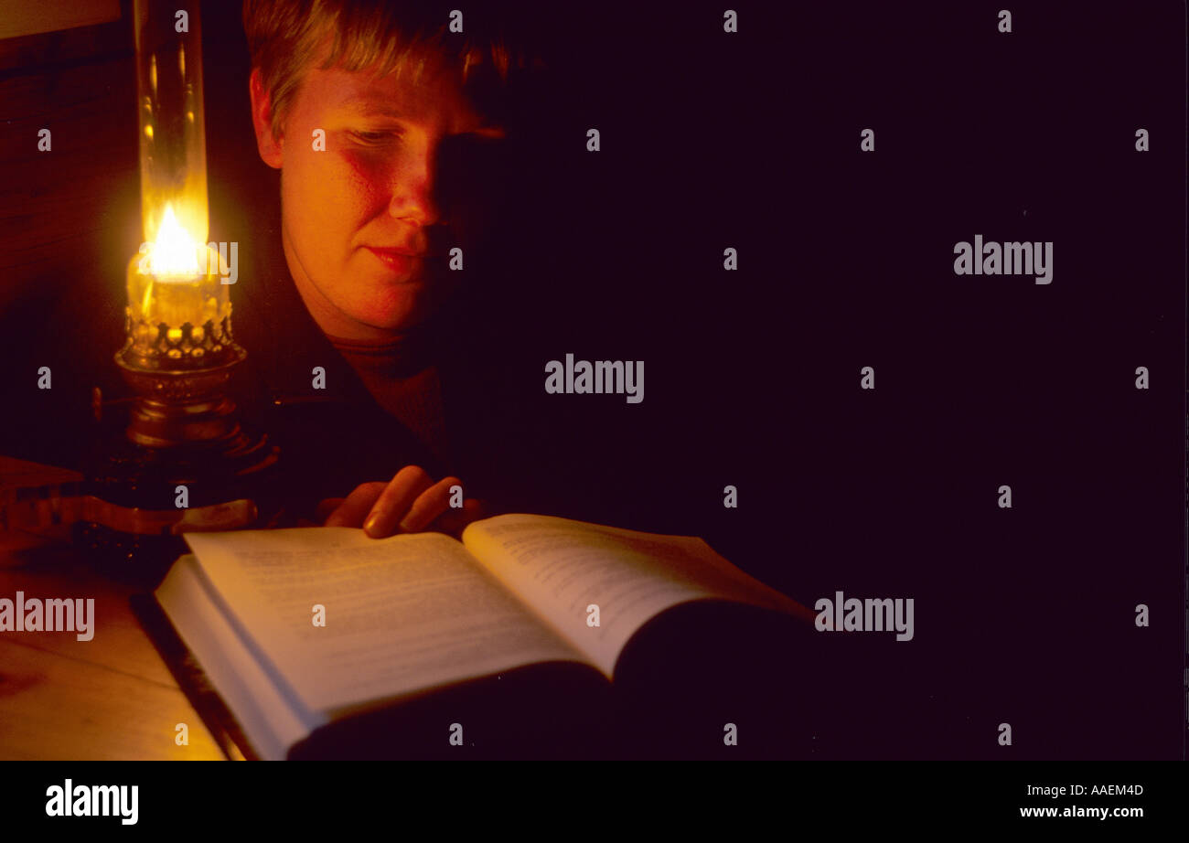 Woman reading book in the light of a kerosene lamp Stock Photo - Alamy